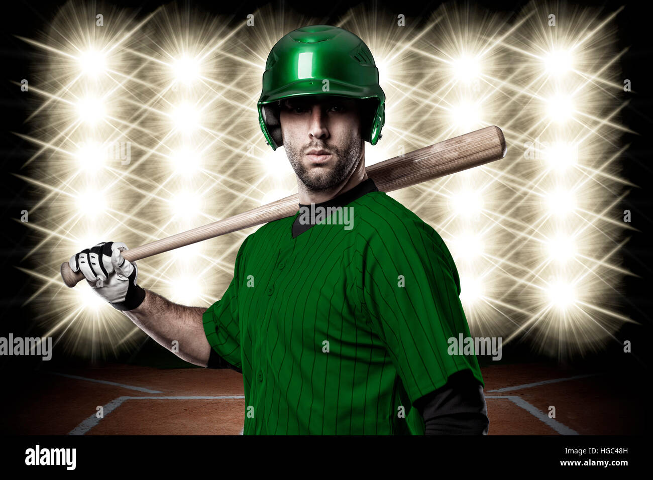 Baseball Player with a green uniform in front of lights Stock Photo - Alamy