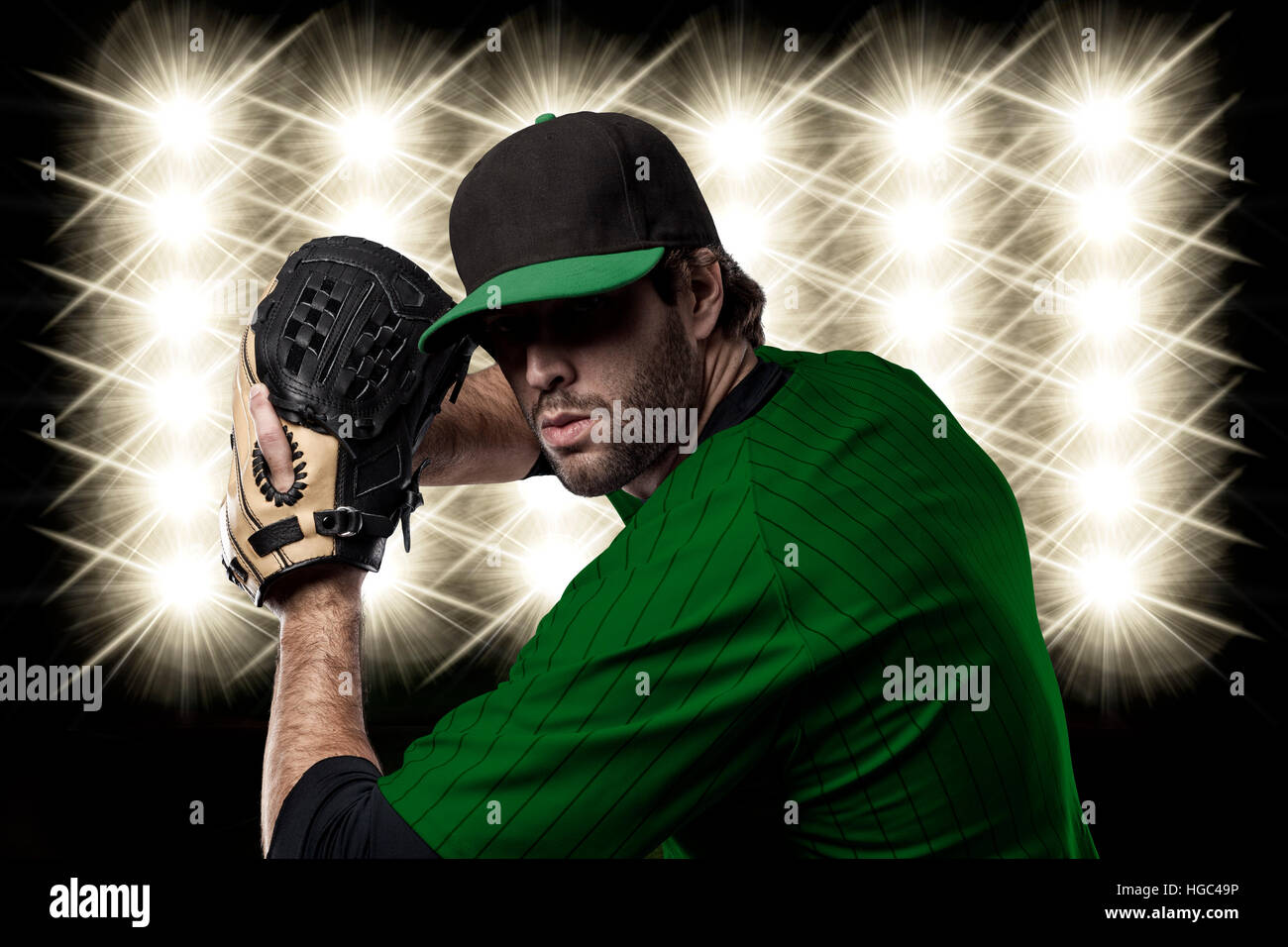 Baseball Player with a green uniform in front of lights Stock Photo - Alamy