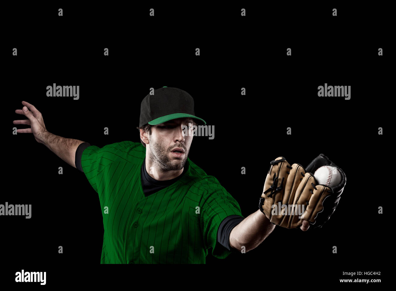 Baseball Player with a green uniform on a black background Stock Photo ...