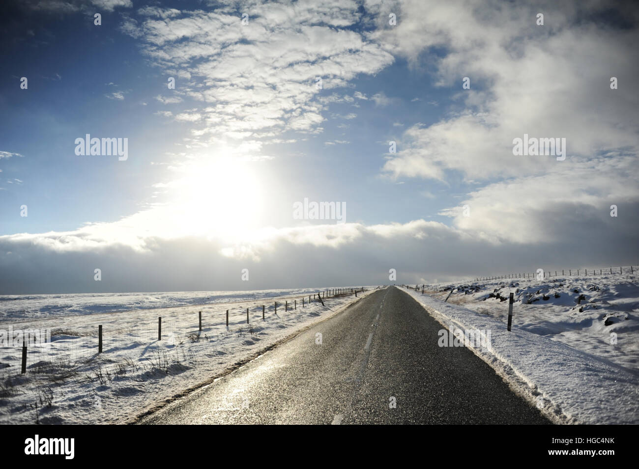 B6114 Saddleworth Road crossing snowy moor top to sun sinking grey ...