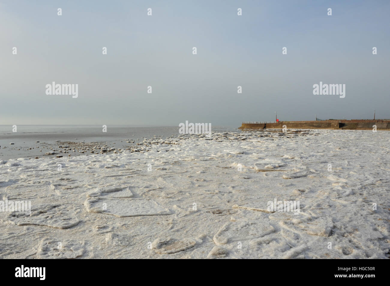 Blue sky hazy clouds view white land-fast sea ice expanse on the beach ...