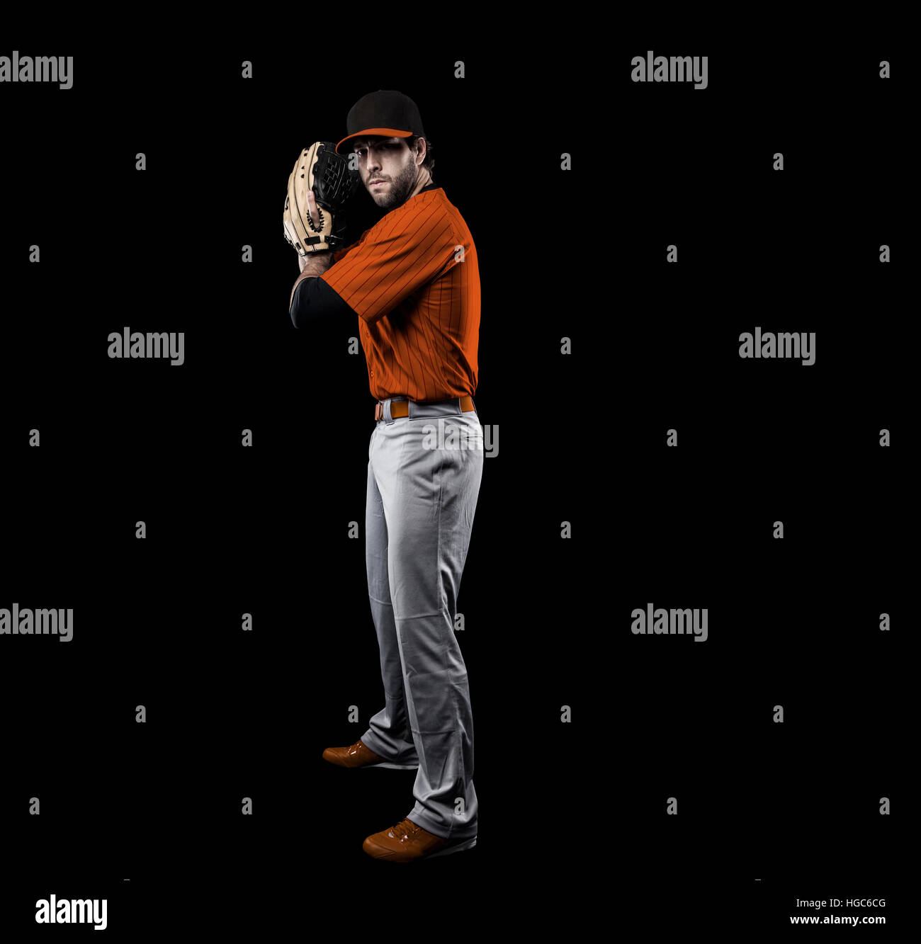 Pitcher Baseball Player with a orange uniform on a black background ...