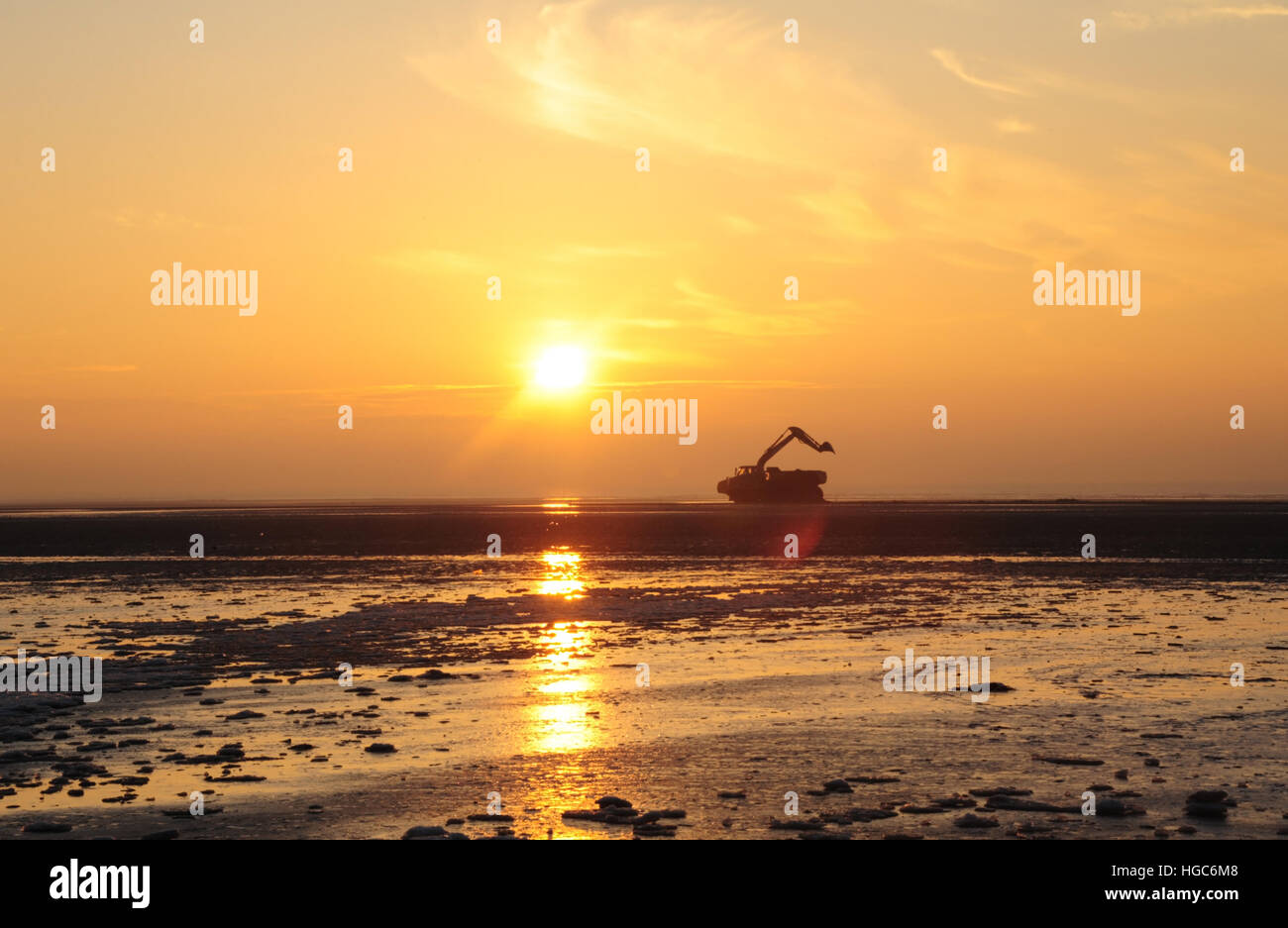 Yellow white sun sinking orange sky, shining sand beach with sea ice ...
