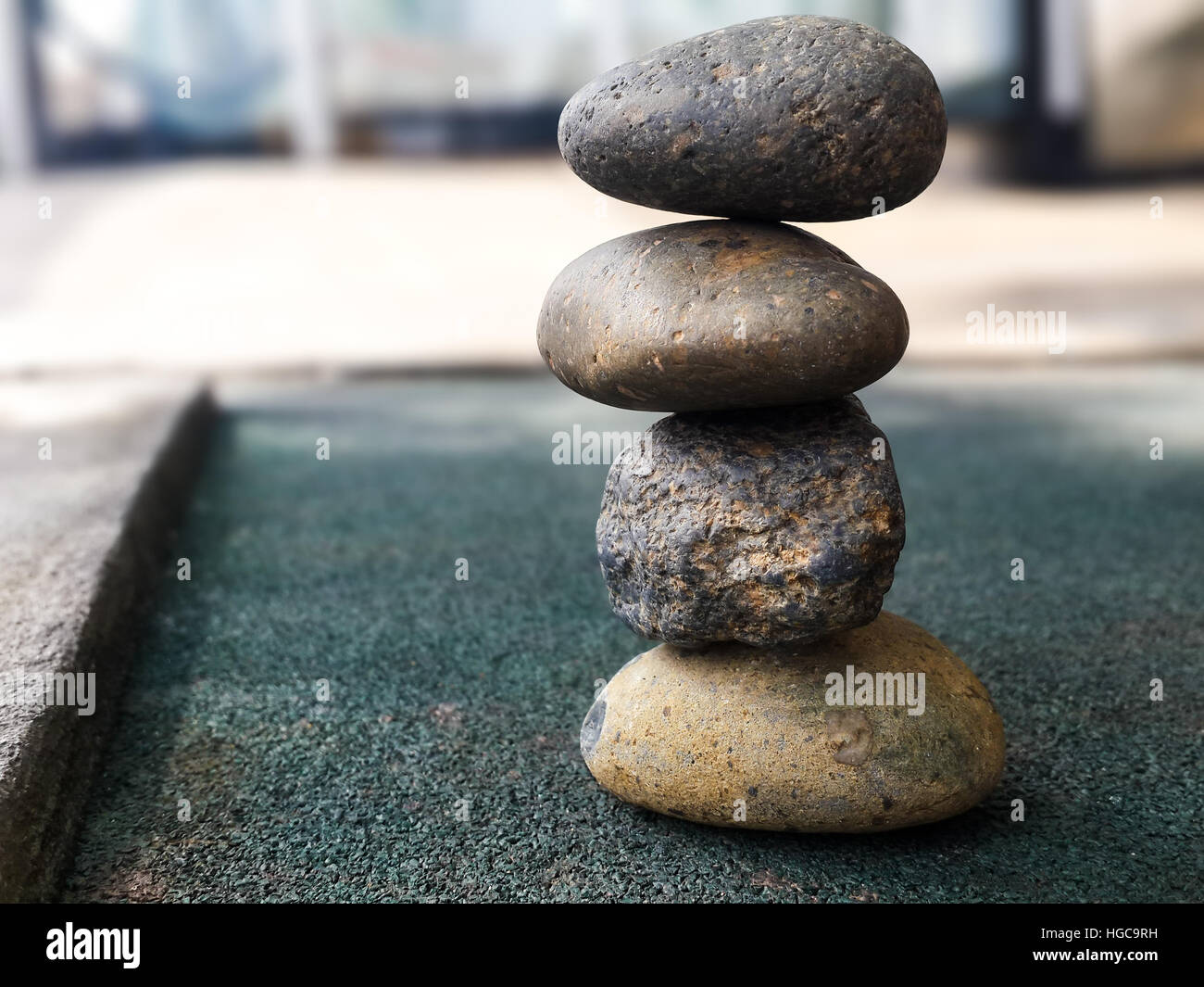 Four stones stacking up in balance on greenish floor Stock Photo - Alamy