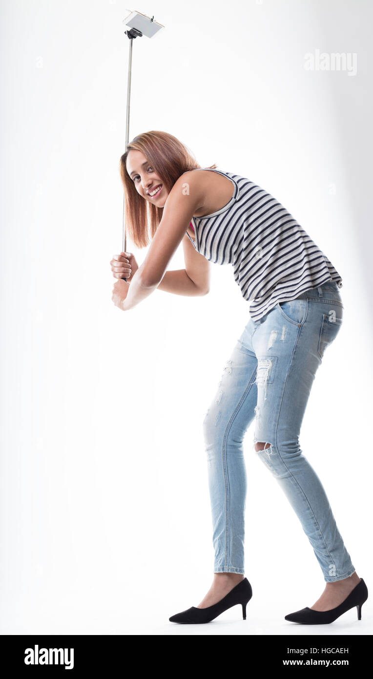 young woman using a selfie stick and a mobile phone as a golf club to ...