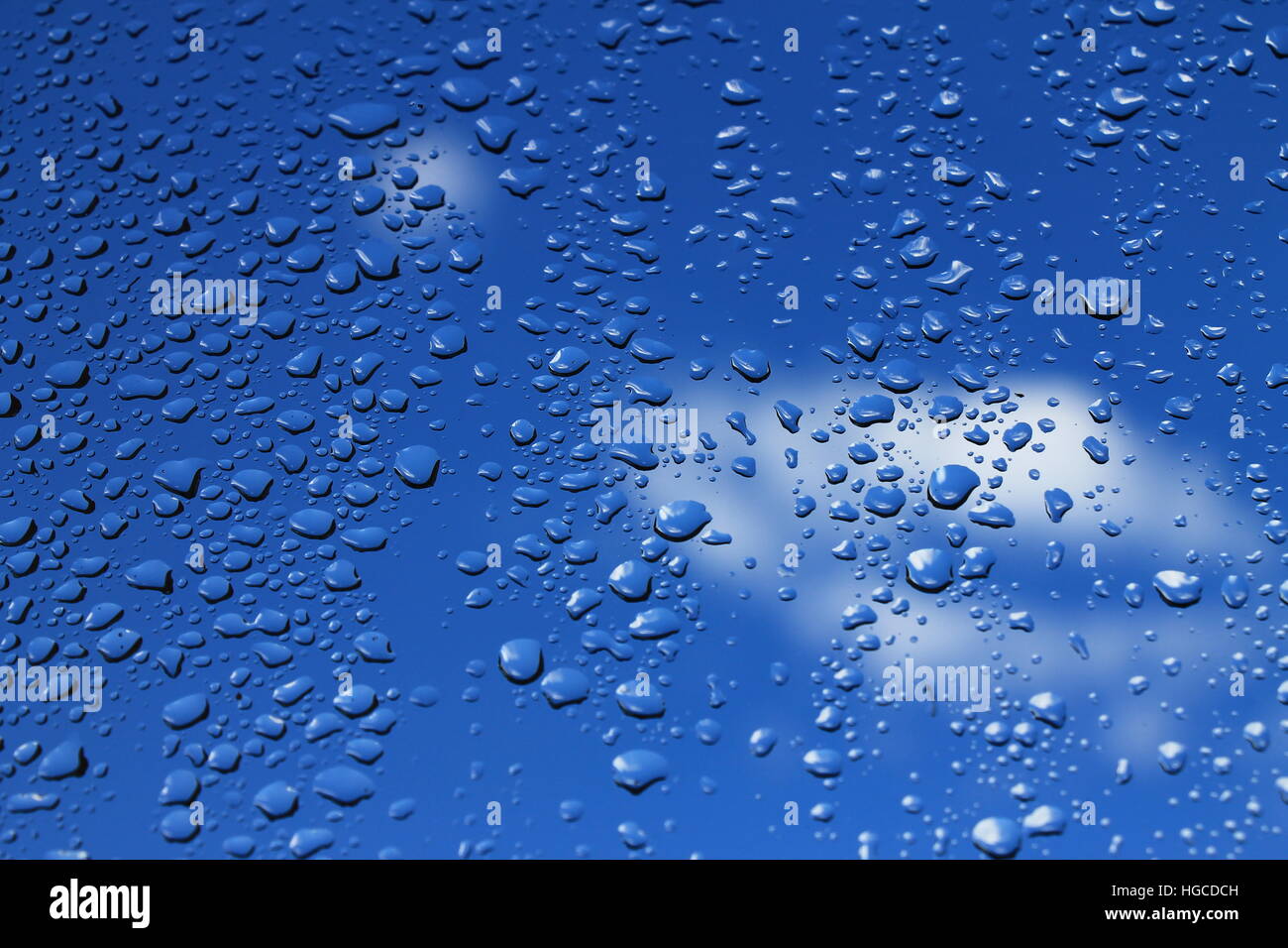 Rain drops on window with blue cloudy sky in background Stock Photo - Alamy