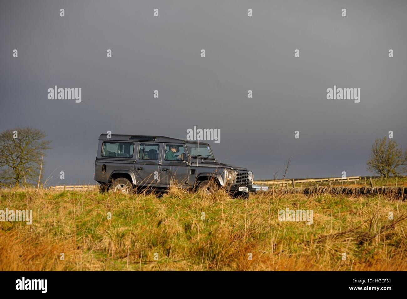 A long wheelbase Land Rover Defender driving down a country B road in ...