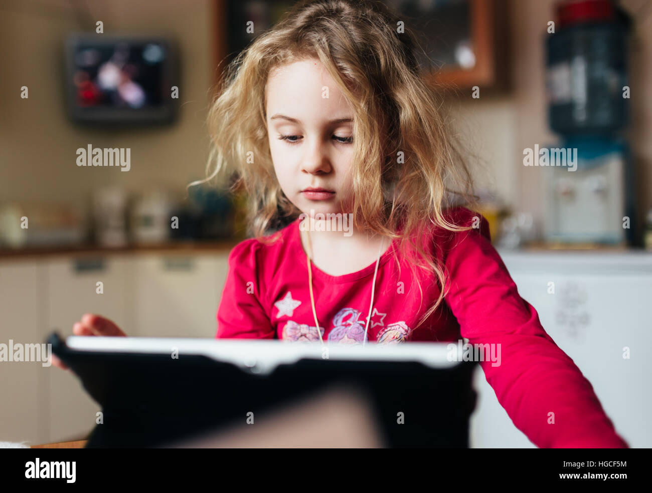 Blonde child girl using tablet computer at home Stock Photo - Alamy