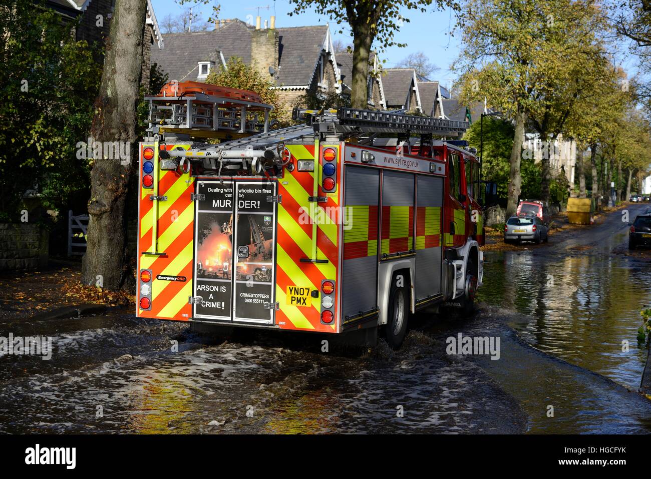 Fire engine driving through flood caused by burst pipe on a suburban ...