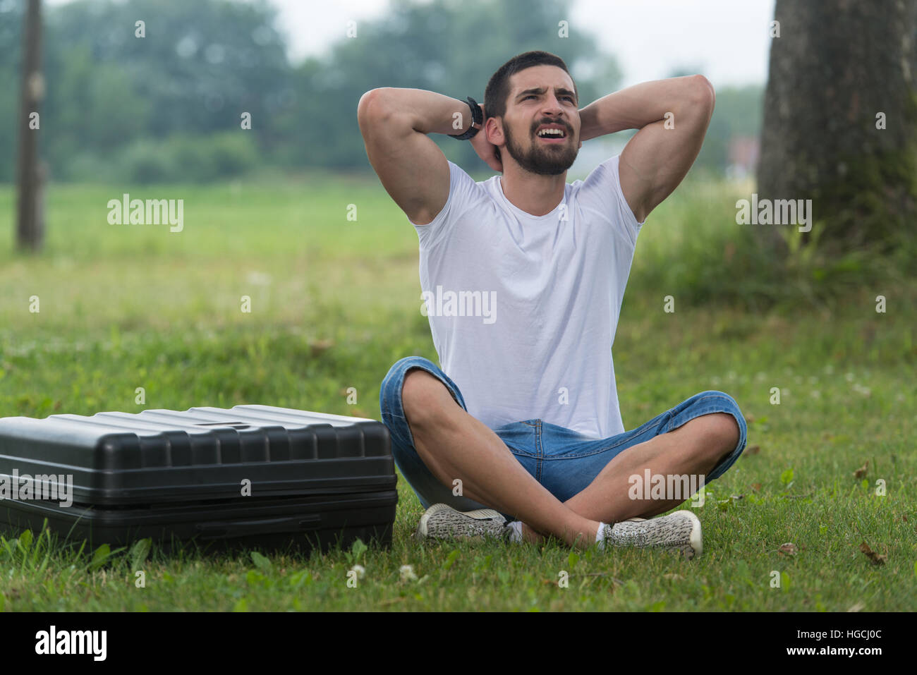 Portrait of Frustrated Young Engineer Sitting On Grass With Case from ...