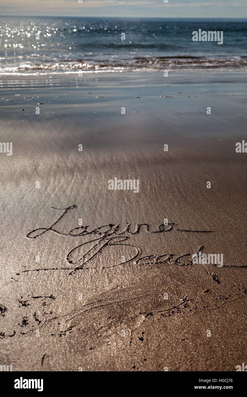 Laguna Beach written in script the wet sand in front of the ocean waves ...
