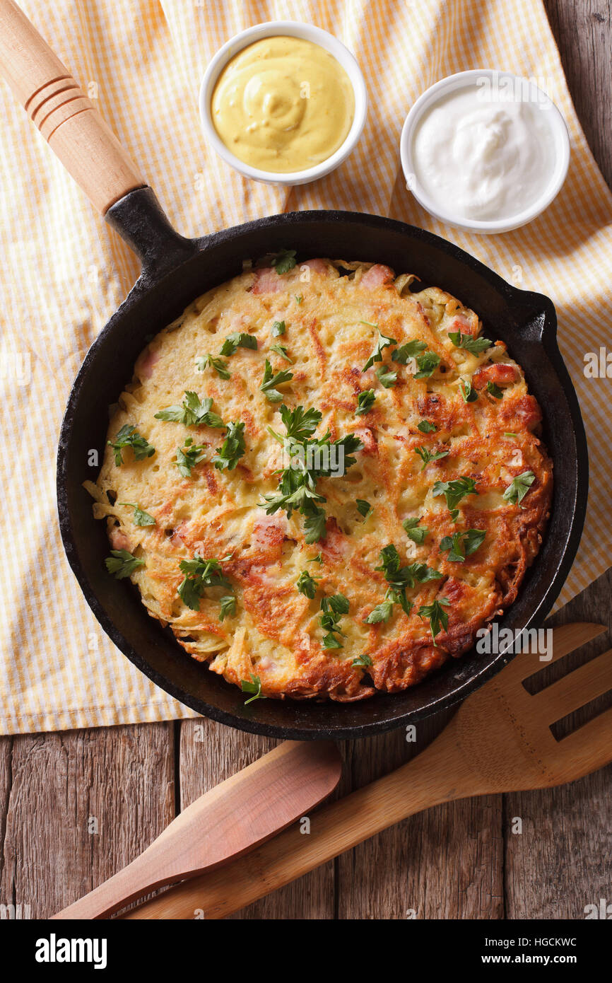 Swiss rosti with herbs close-up in a frying pan on the table. vertical ...