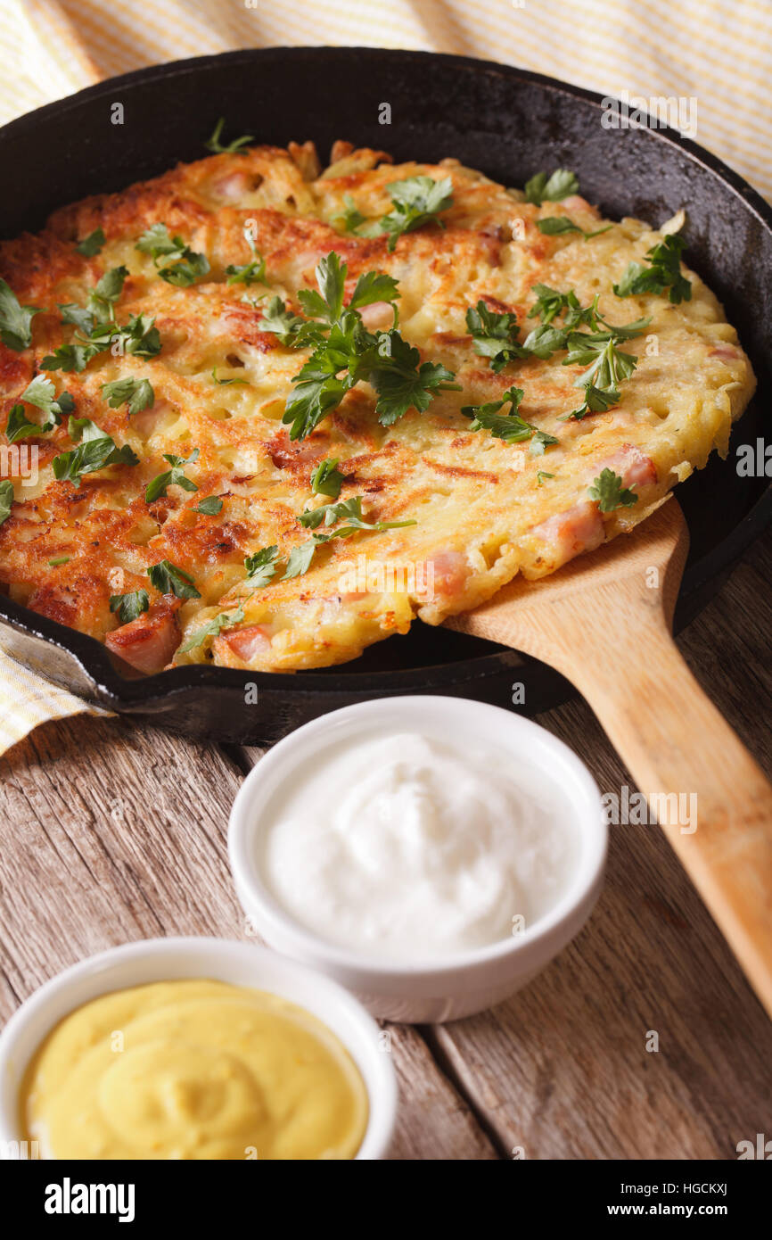 Potato rosti with herbs close-up in a frying pan on the table. vertical ...