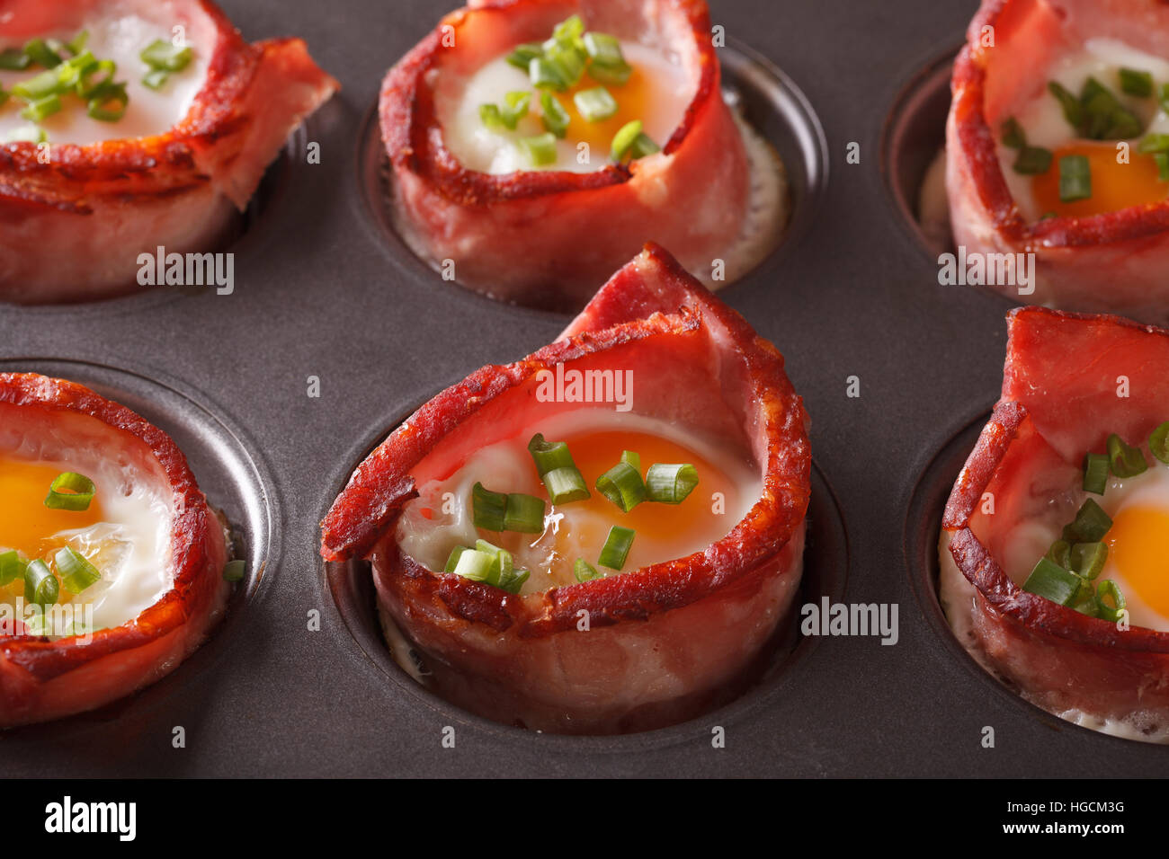 freshly baked hot eggs wrapped in bacon close up in baking dish ...