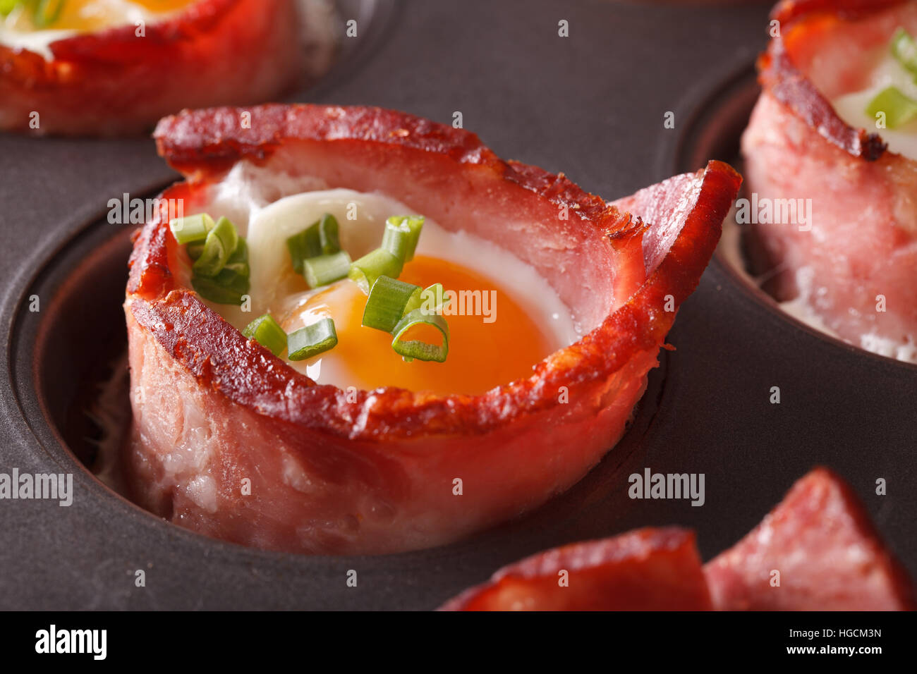 Baked eggs wrapped in crispy bacon macro in baking dish. Horizontal ...