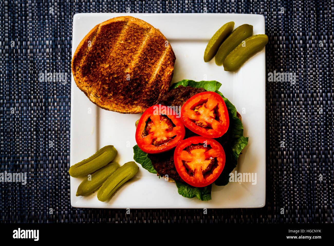 A Hamburger on a toasted whole wheat bun with lettuce tomato and ...