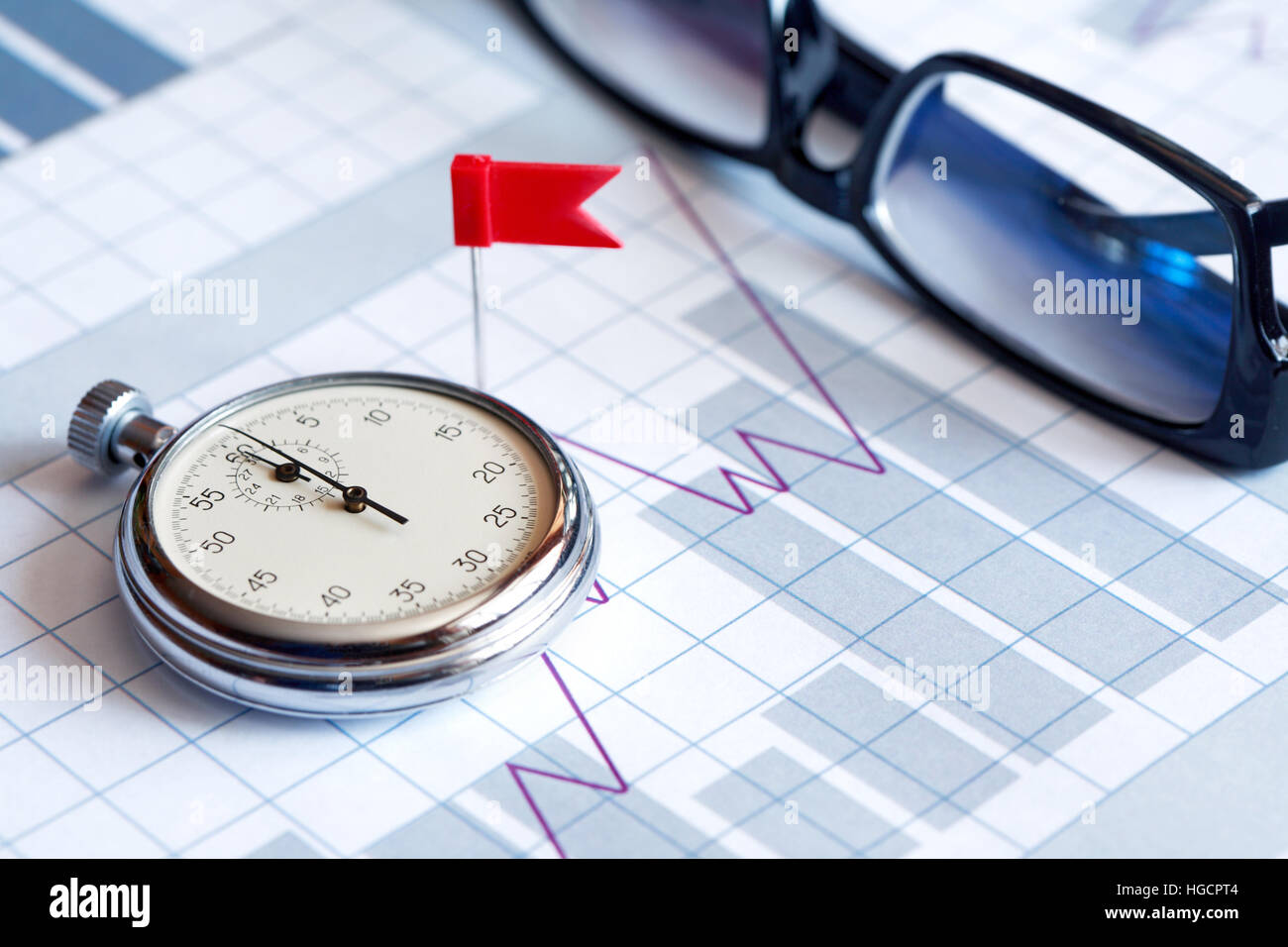 Business concept. Red flag thumbtack near stopwatch and spectacles on ...