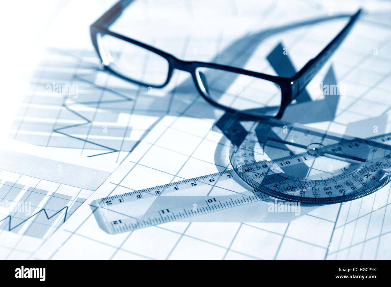 Two rulers near spectacles on paper background with business chart ...