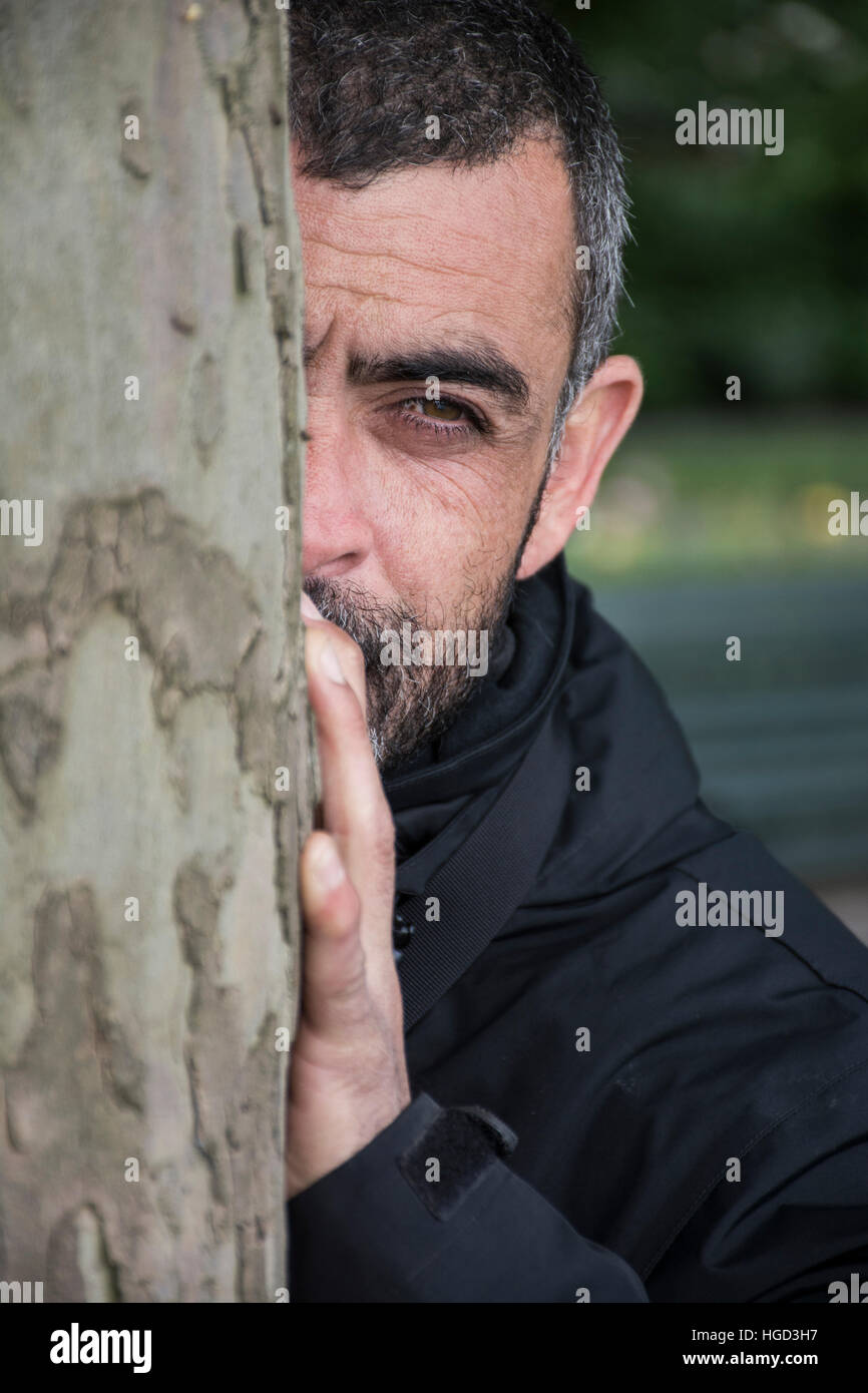 Man peeking behind tree hi-res stock photography and images - Alamy