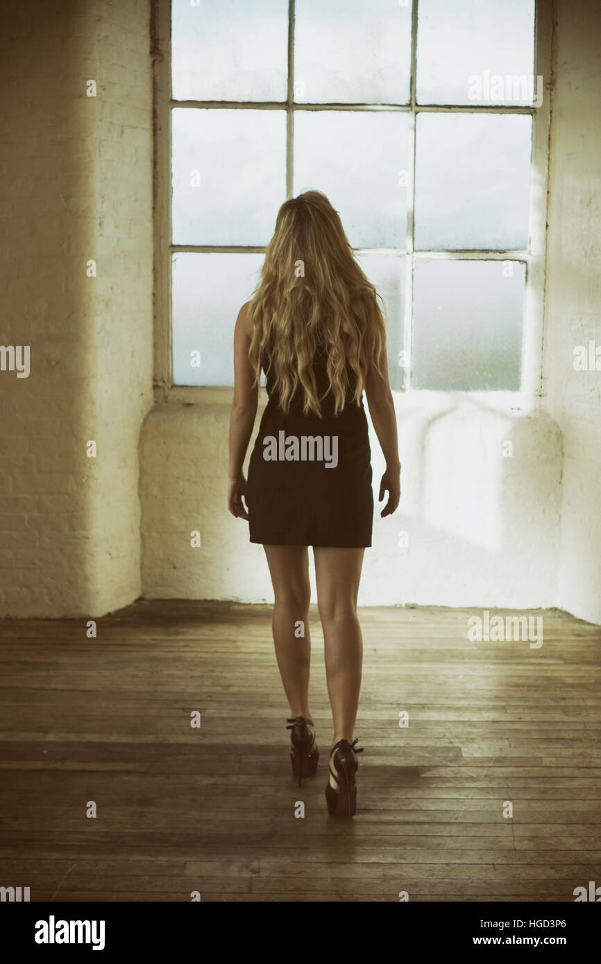 Rear view of a woman walking towards the window Stock Photo - Alamy