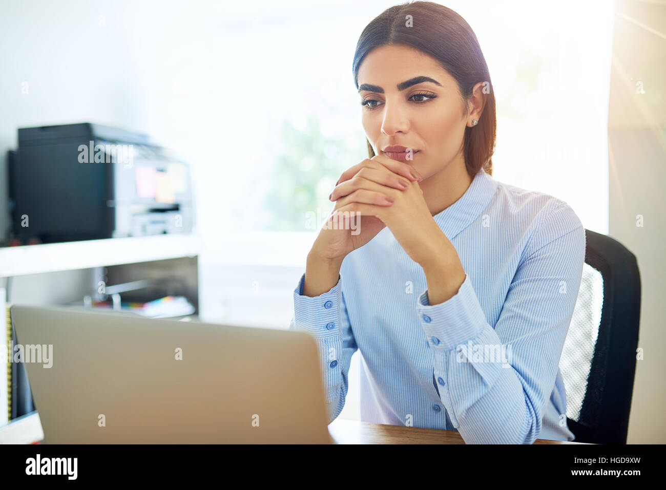Sad looking young adult female with folded hands staring at something ...