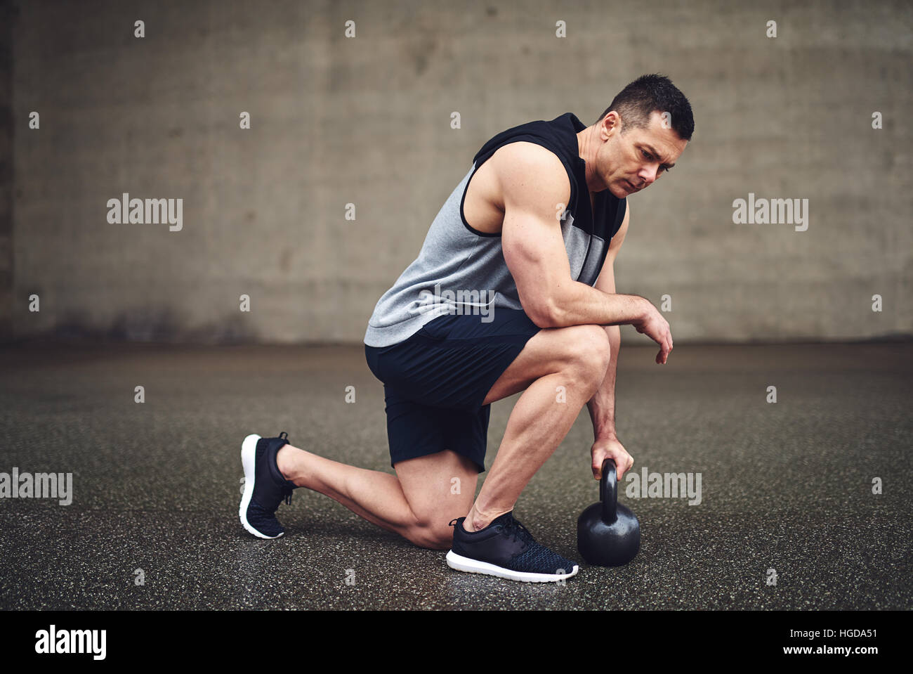 Full length shot of young man in sportswear sitting and bending on one ...