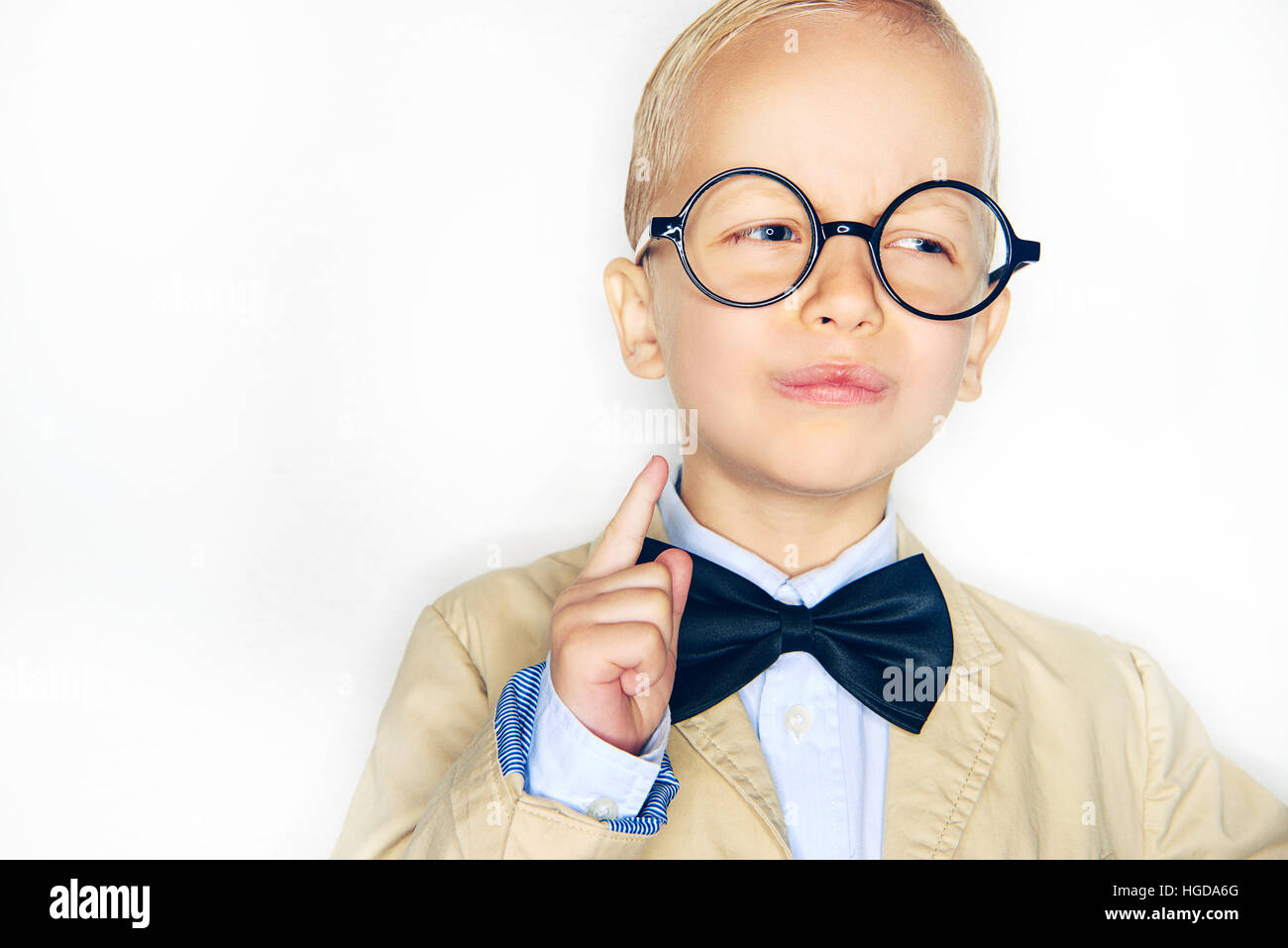 Little boy in formal suit and glasses with proud face holding finger up ...