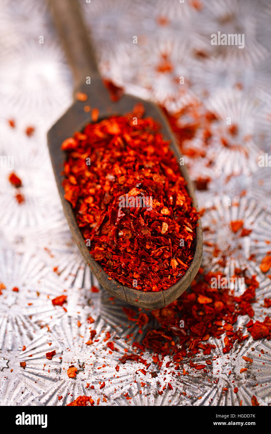 red hot chillies pepper flakes in vintage wooden spoon on textured ...