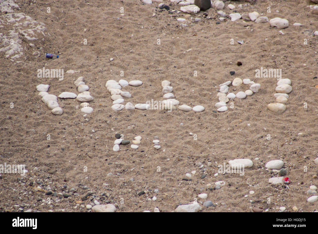 Help written in pebbles in sand Stock Photo - Alamy