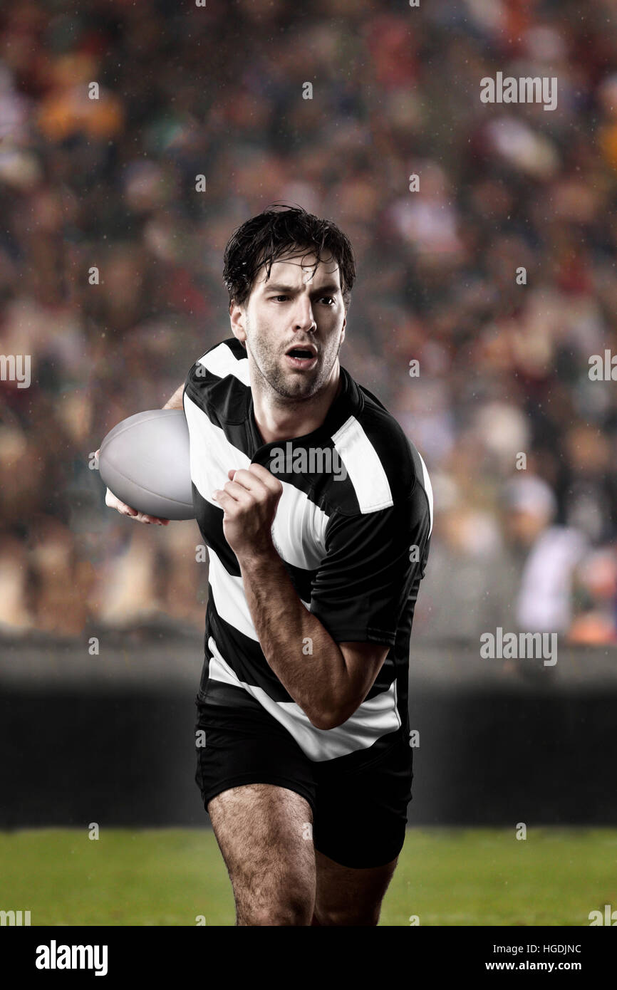 Rugby player in a black and white uniform running on a stadium Stock ...
