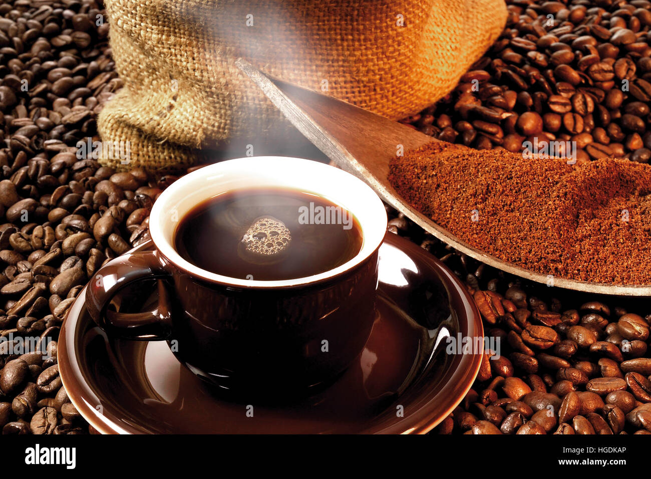 Coffee in a brown cup with ground coffee atop a bed of coffee beans ...