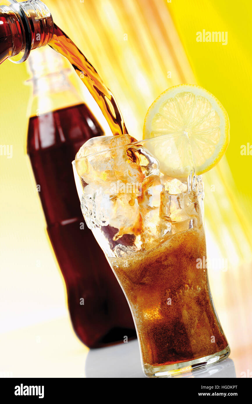 Pouring Coke into a glass with ice cubes, bottle of Cola in background ...