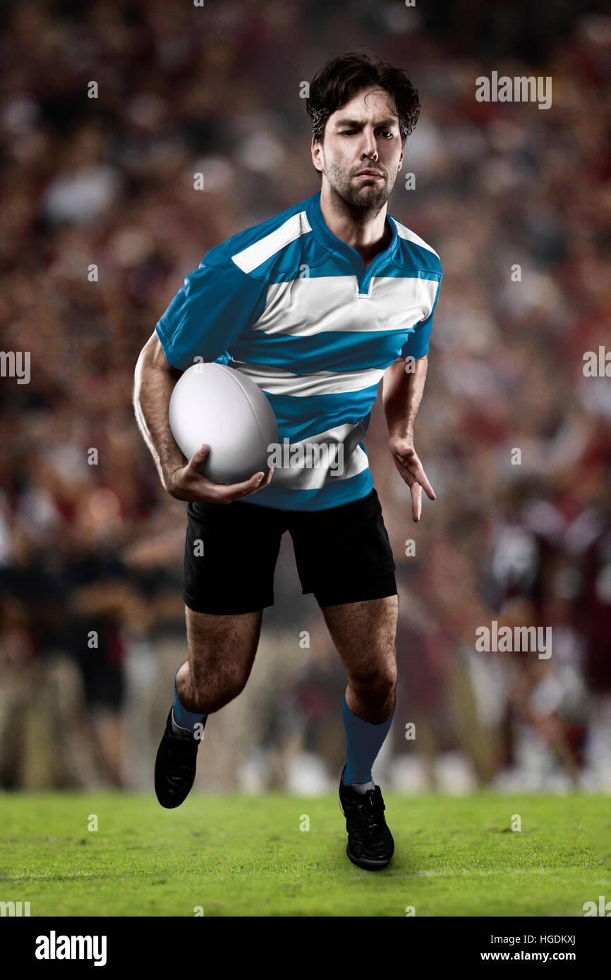 Rugby player in a blue uniform running on a stadium Stock Photo - Alamy
