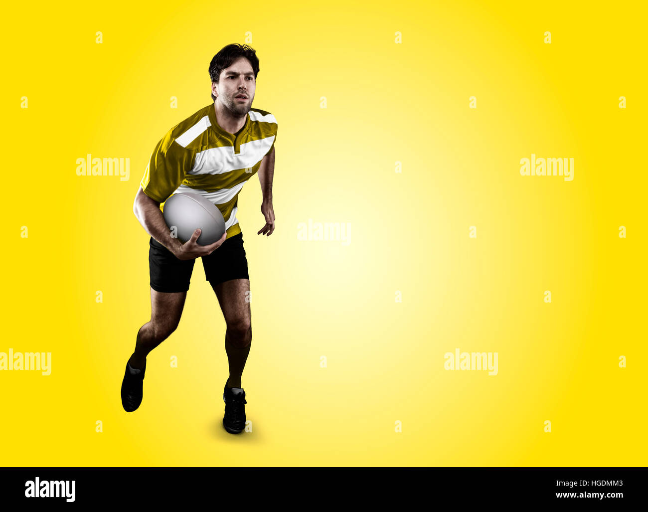 Rugby player in a yellow uniform running on a yellow background Stock ...