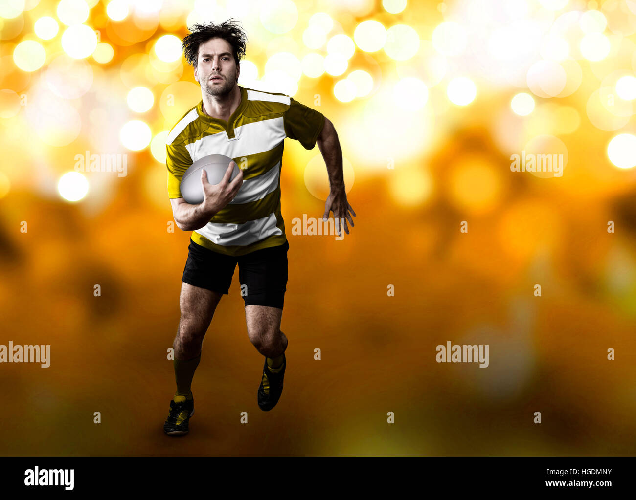 Rugby player in a yellow uniform running on a yellow lights background ...