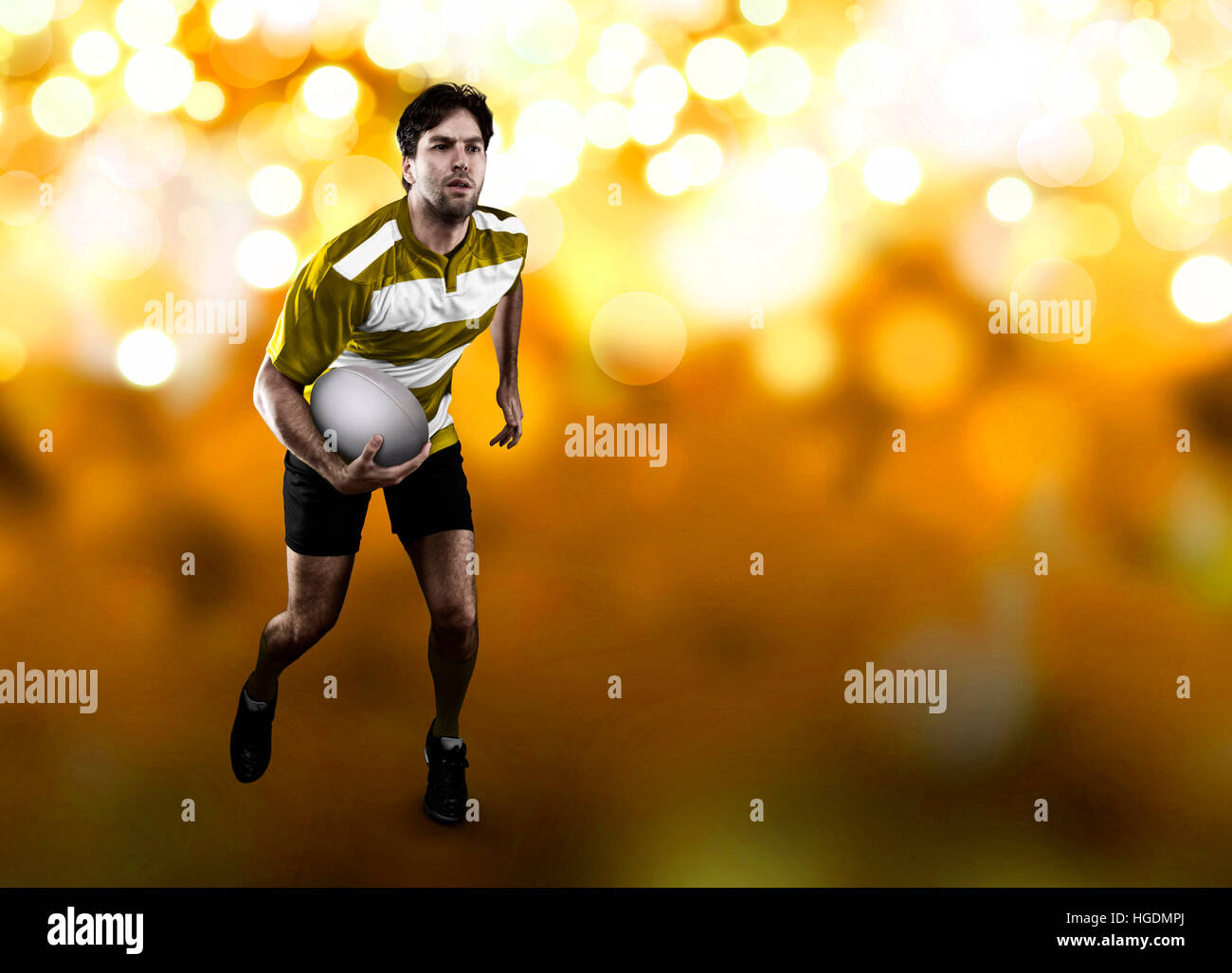 Rugby player in a yellow uniform running on a yellow lights background ...