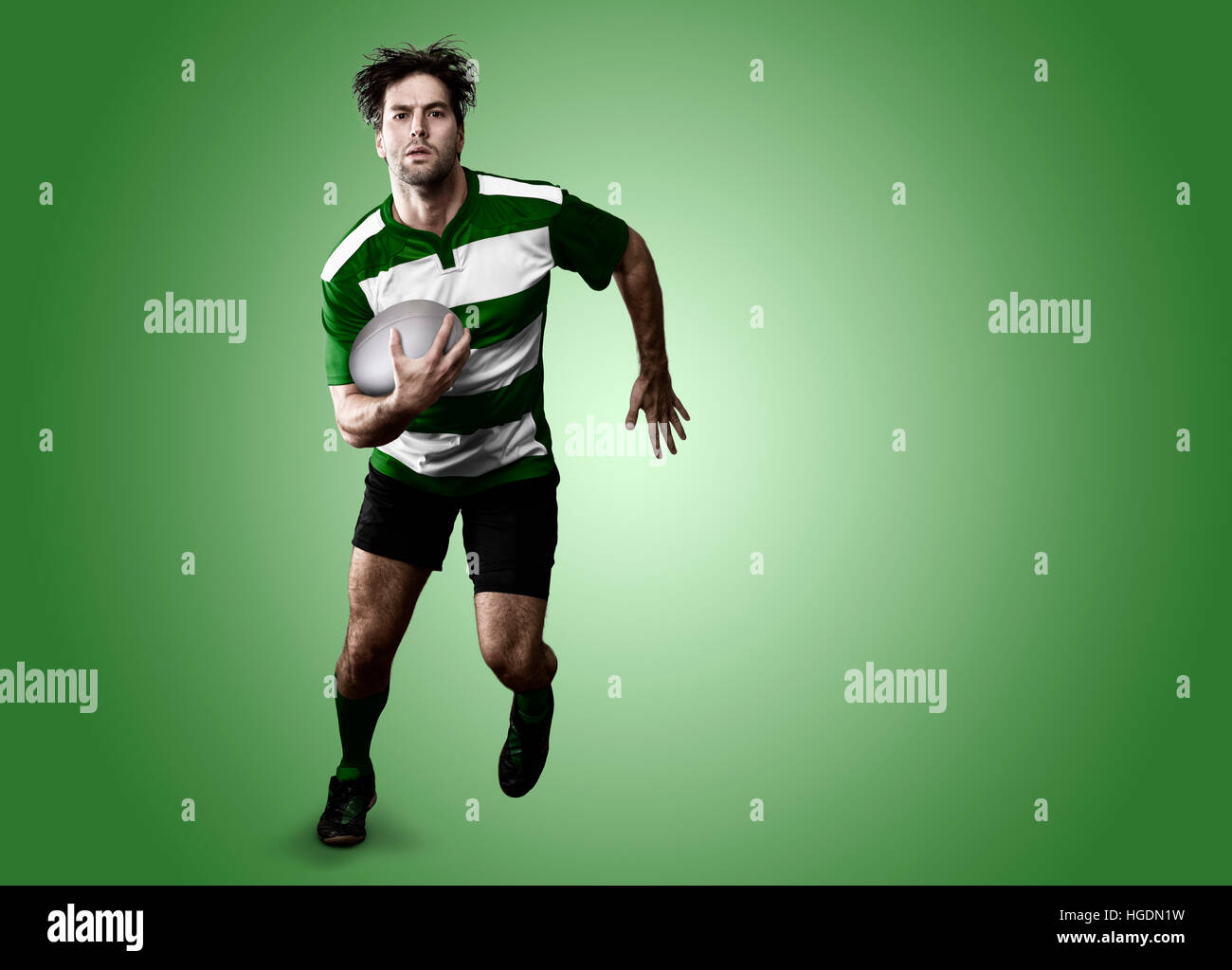 Rugby player in a green uniform running on a green backgrond Stock ...