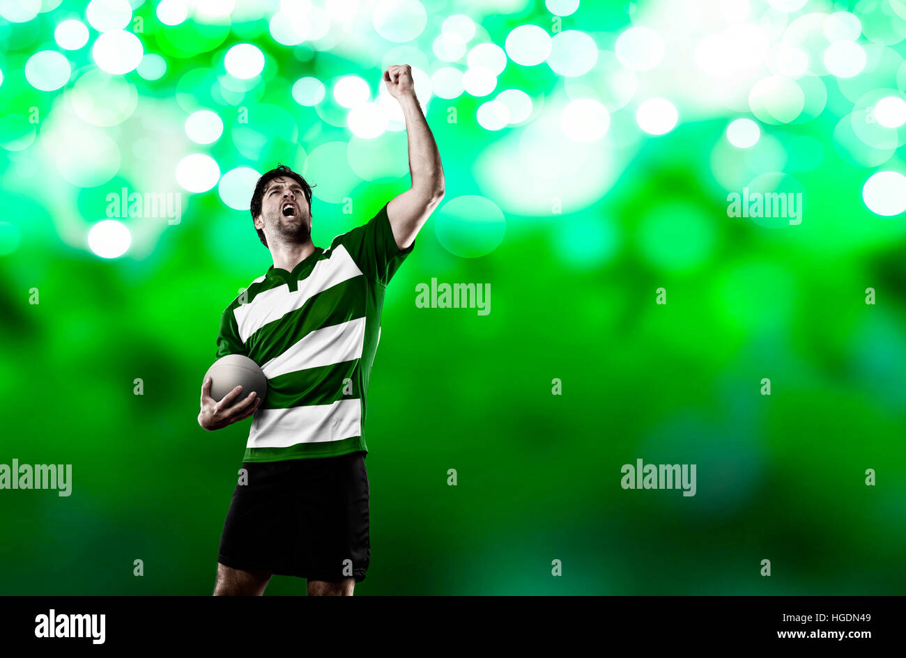 Rugby player in a green uniform celebrating on a green lights backgrond ...