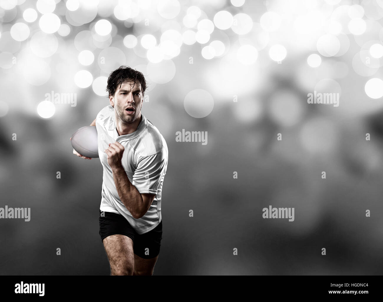 Rugby player in a white uniform running on a white lights background ...