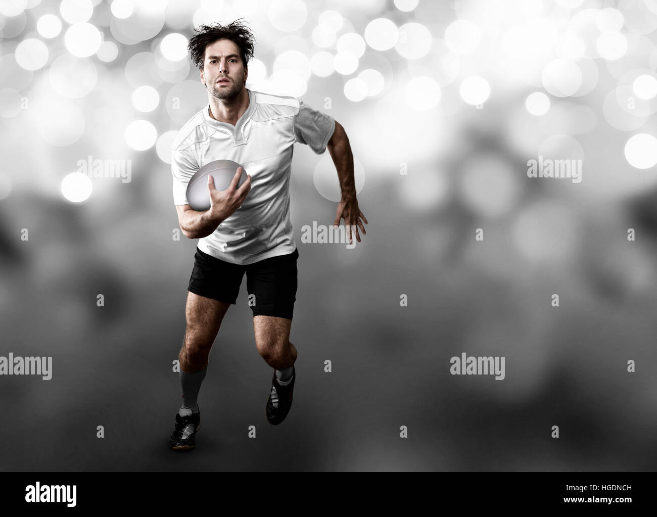 Rugby player in a white uniform running on a white lights background ...