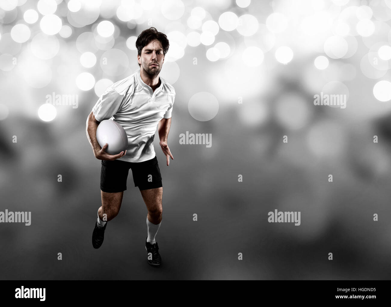 Rugby player in a white uniform running on a white lights background ...