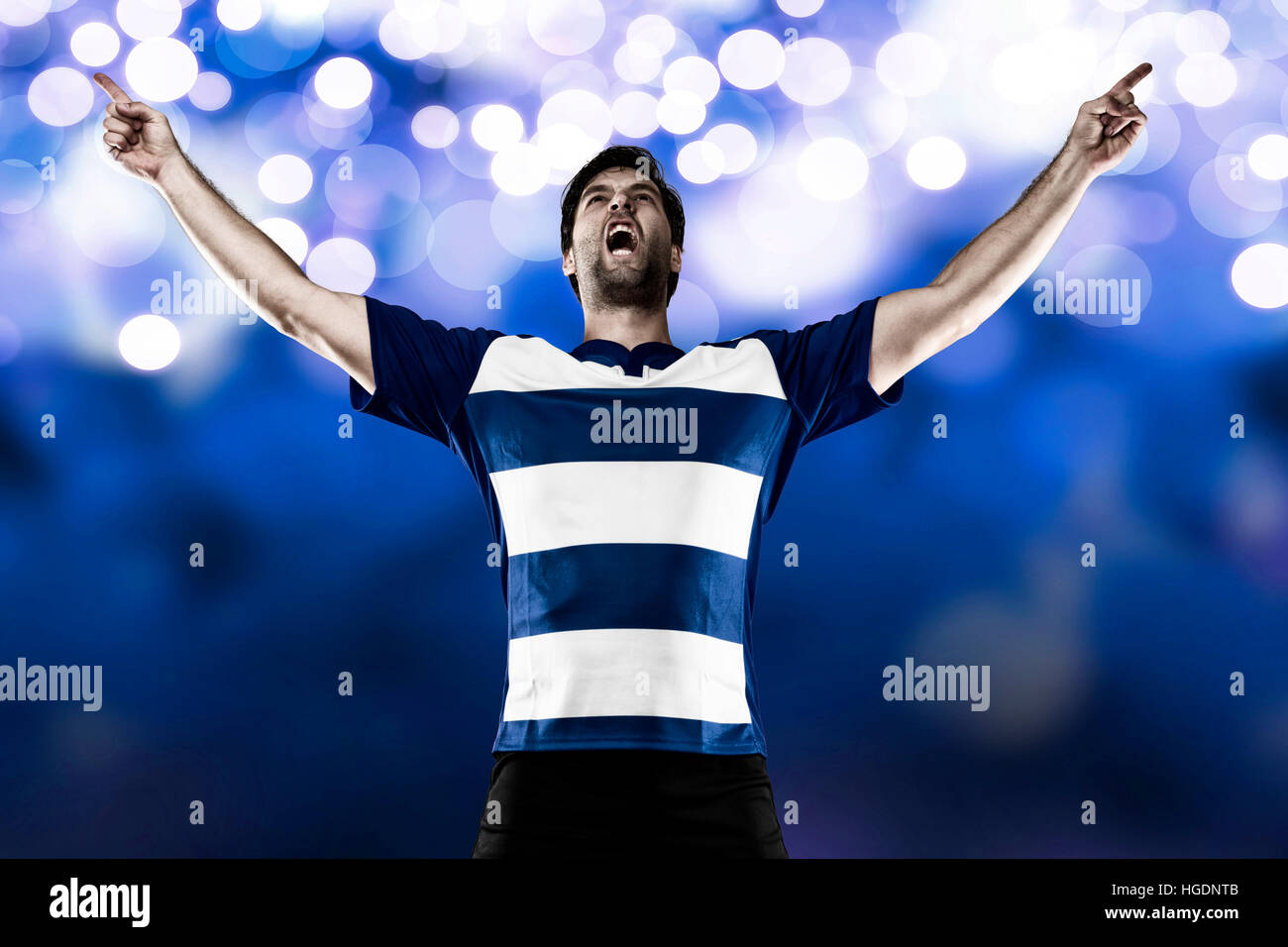 Rugby player in a blue uniform celebrating on a blue lights background ...