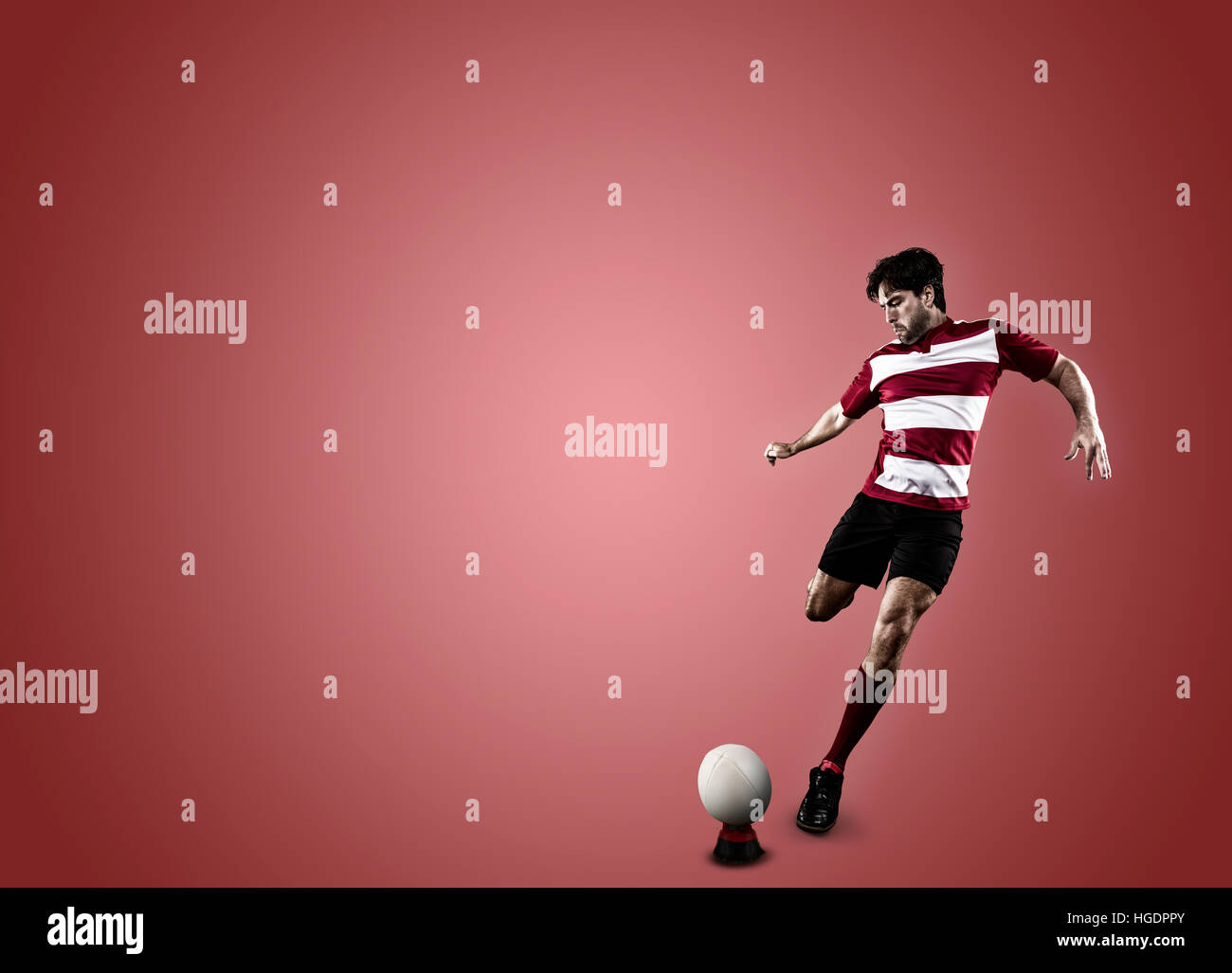 Rugby player in a red uniform kicking a ball on a red background Stock ...