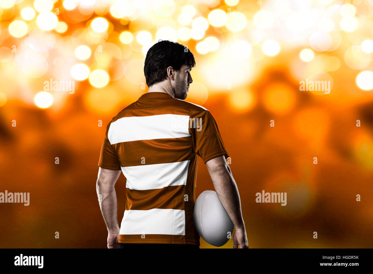 Rugby player in a orange uniform on a orange lights background Stock ...