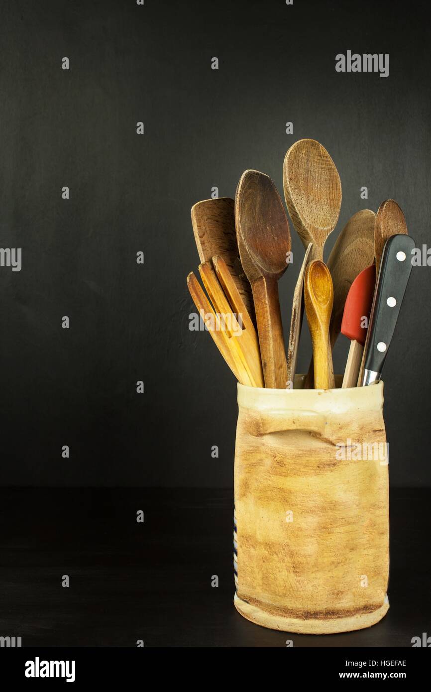 Tools cook on a wooden shelf. Kitchen utensils in a ceramic container ...