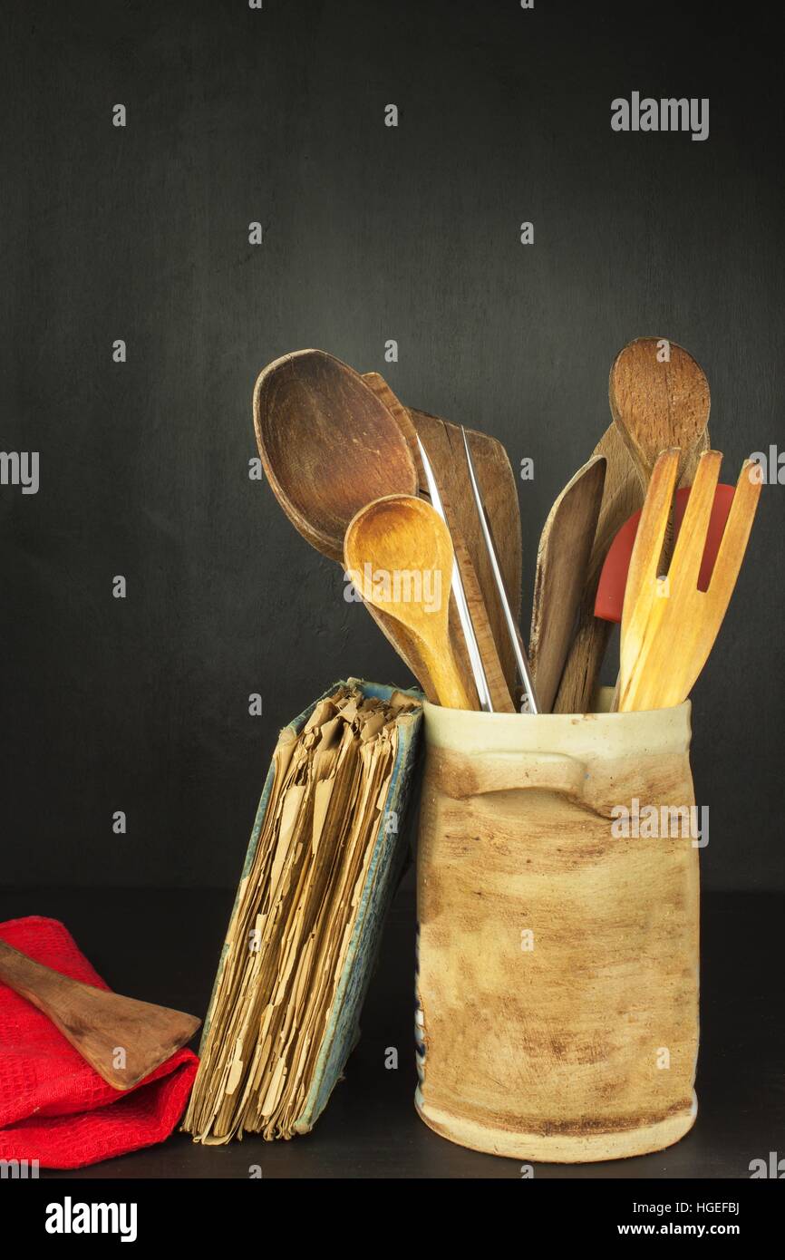 Tools cook on a wooden shelf. Kitchen utensils in a ceramic container ...