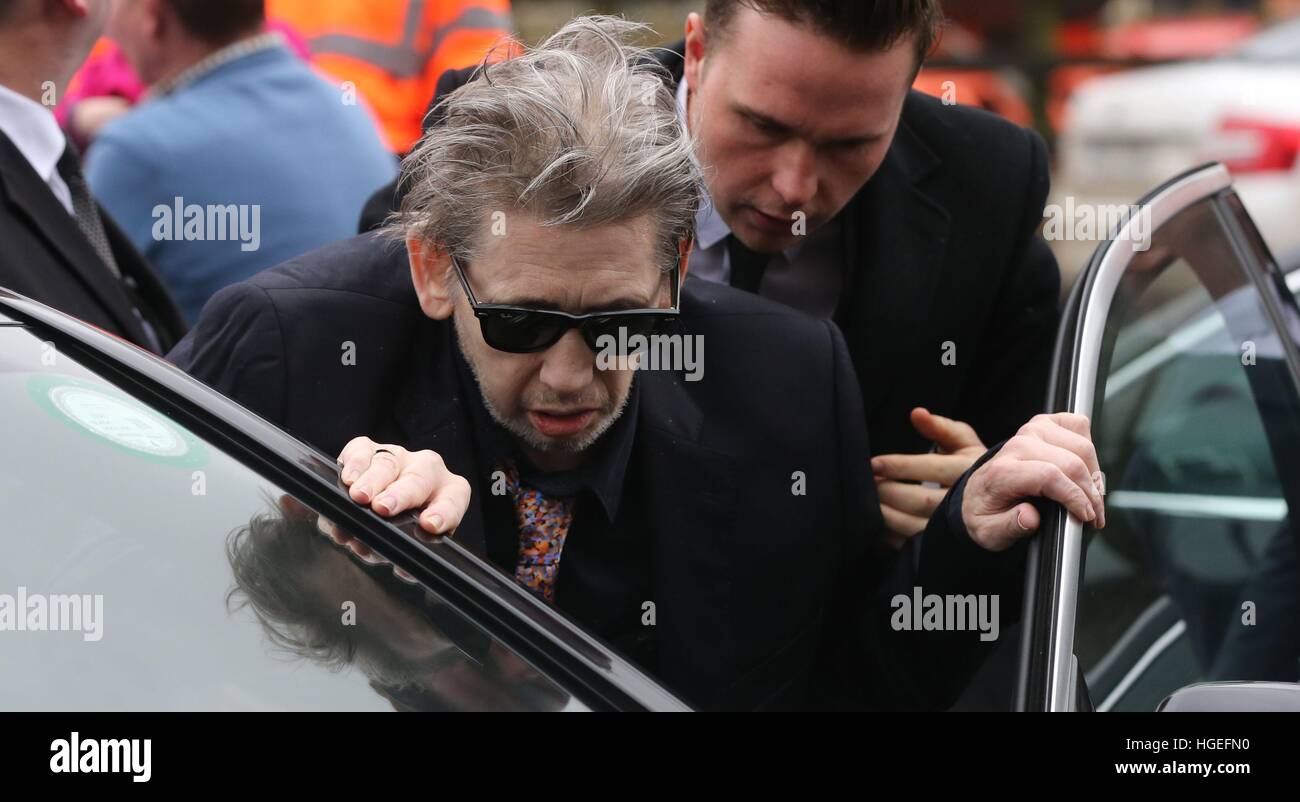 Singer Shane MacGowan is helped from the church as the funeral of his ...
