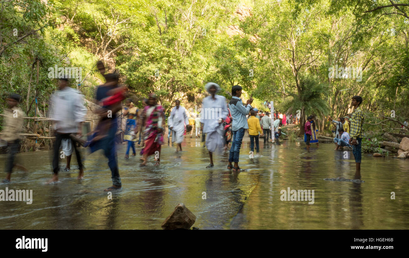 A large group of Hindu pilgrims walking through a forest path to the ...