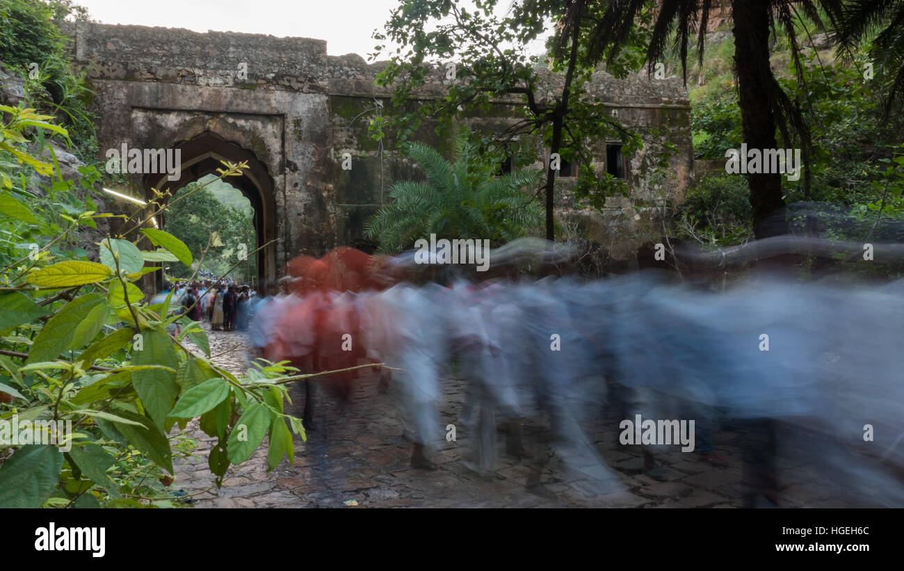A large group of Hindu pilgrims walking through a forest path to the ...