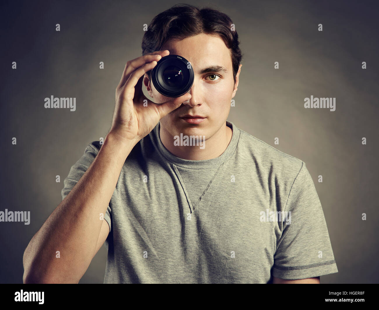 Young man photographer holding a lens in his eye. Lens as eye Stock ...